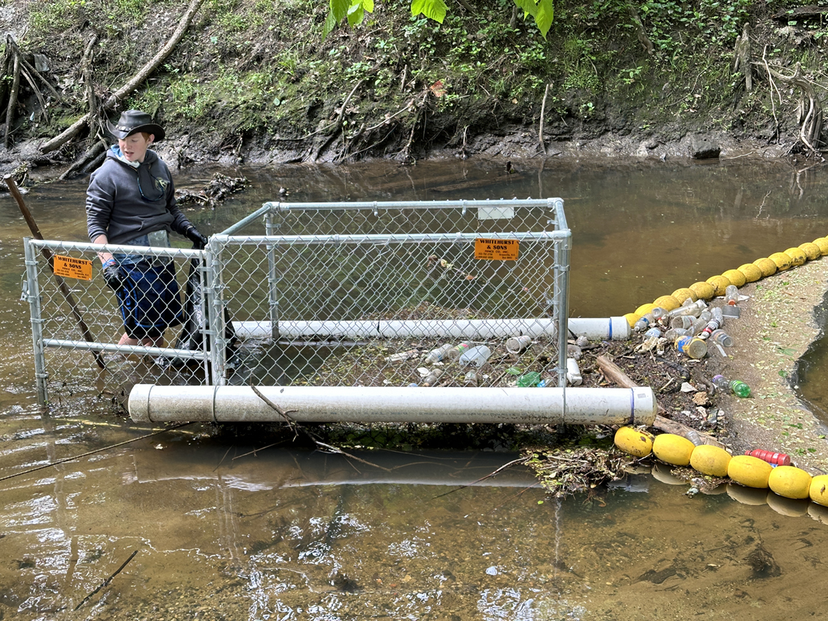 Scout earns volunteer hours with trash trap cleanout